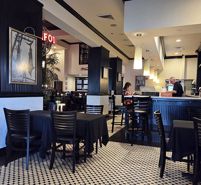 The bar area balances sophistication with comfort, where classic black and white tiles meet warm lighting and the promise of perfectly paired libations.