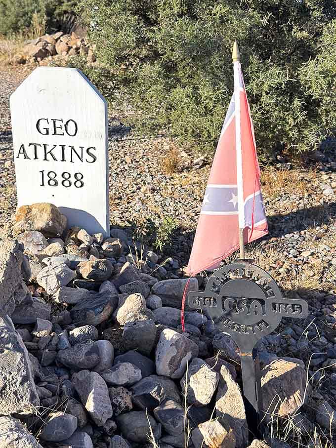 George Warren Atkins' 1888 marker sits adorned with flags and mementos, proving that visitors still honor these long-gone pioneers.