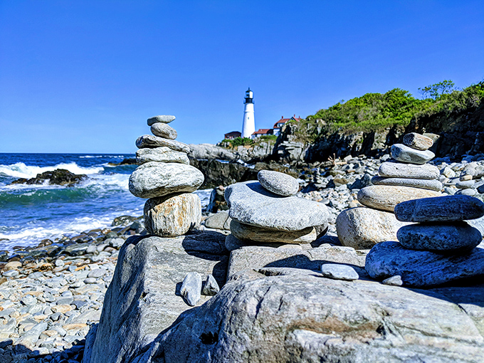 Carefully balanced stone cairns dot the shoreline near Portland Head Light, temporary monuments created by visitors marking their pilgrimage.