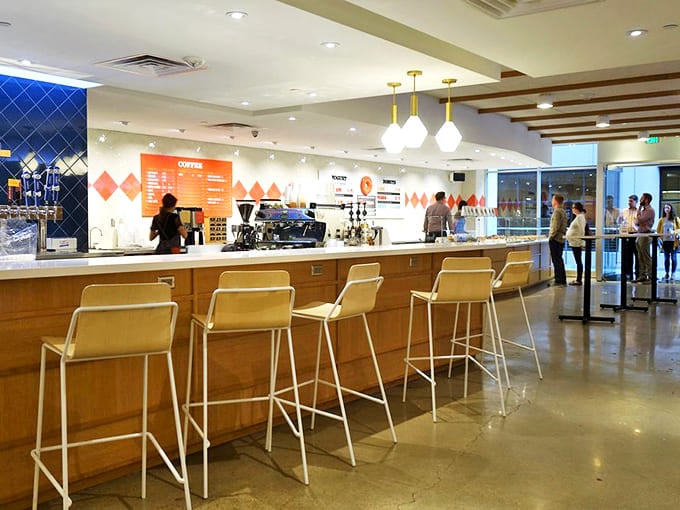 Counter seating offers front-row views of the donut-making magic while modern wooden chairs invite you to linger over coffee.