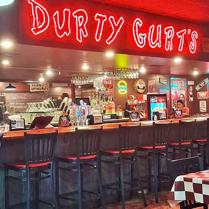 The bar area glows with neon warmth, inviting you to settle in for drinks and conversation between burger bites.