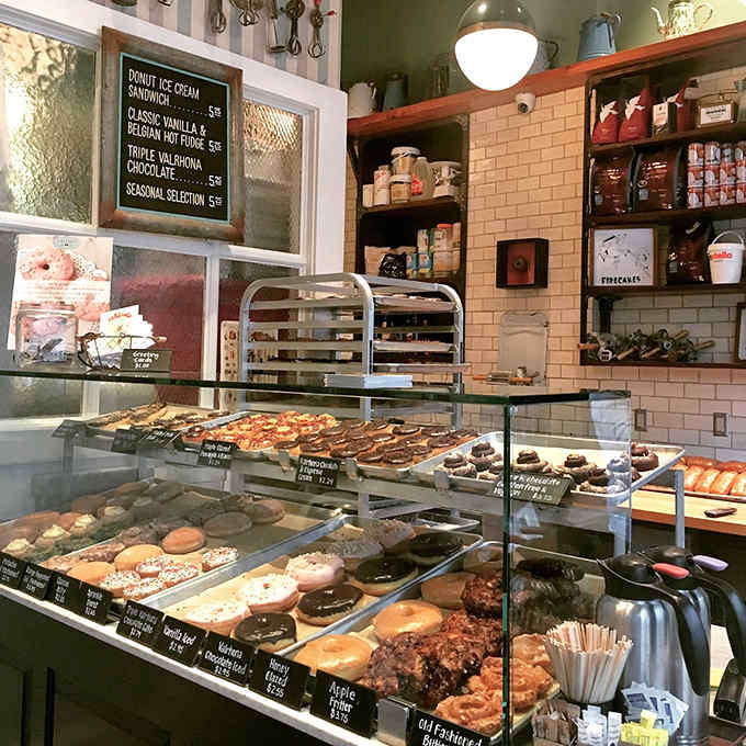 The display case presents fresh donuts like edible jewelry, each one deserving careful consideration before you make your inevitably difficult selection.