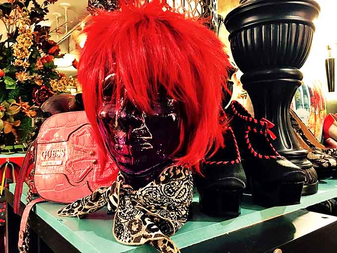 A red wig crowns a display with theatrical flair, because sometimes vintage shopping requires a sense of humor and adventure.
