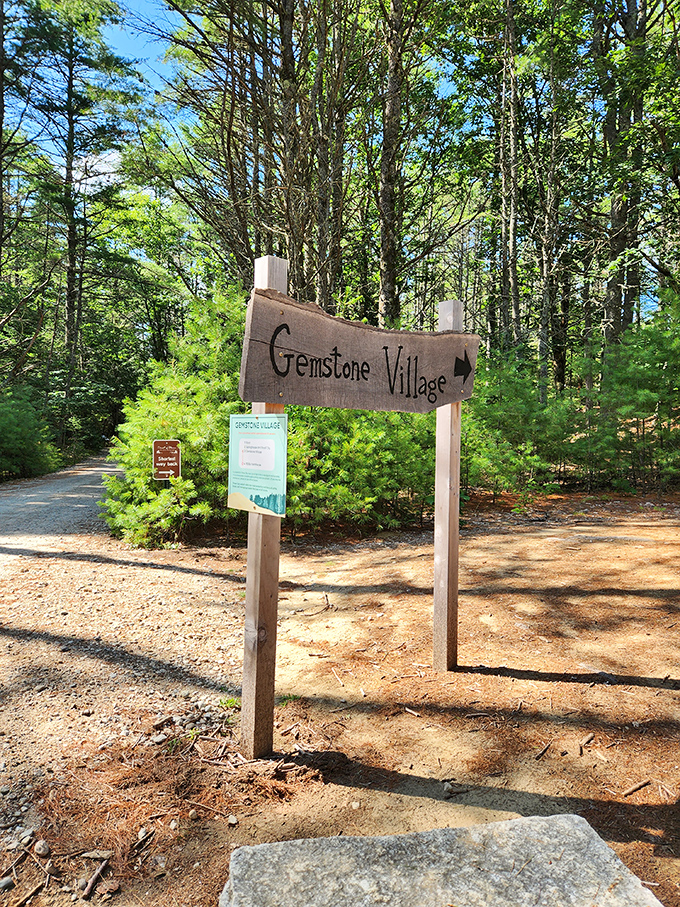 The Gemstone Village sign points the way to treasure hunting adventures, where Maine's sandy anomaly yields colorful mineral souvenirs.