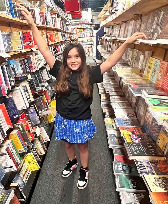 Young readers discover the magic of bookstores, where arms stretched wide still can't encompass all the adventures waiting on these packed shelves.