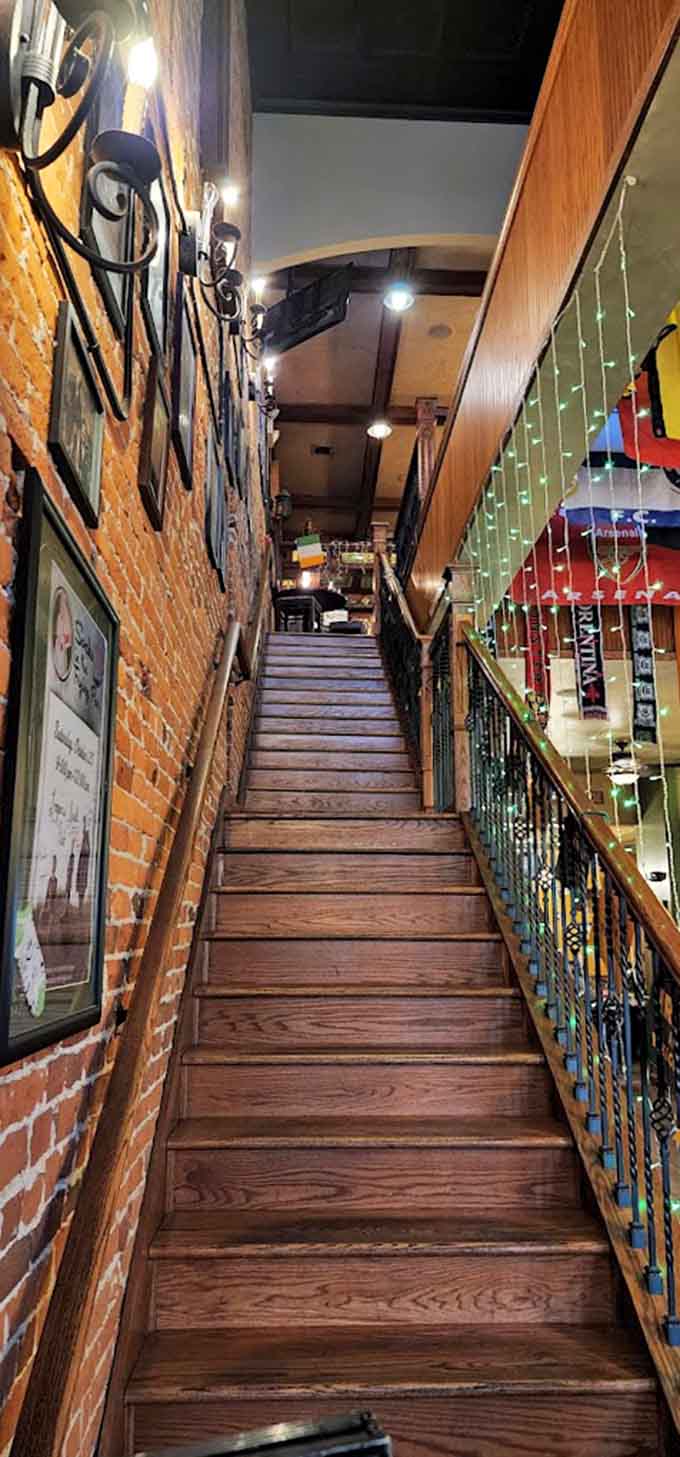 Those wooden stairs with exposed brick walls lead to more dining space, adding to the authentic multi-level pub experience.