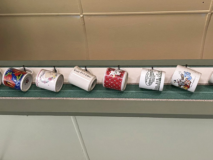 Vintage coffee mugs march along the wall like soldiers of nostalgia, each one adding character to this authentically retro space.