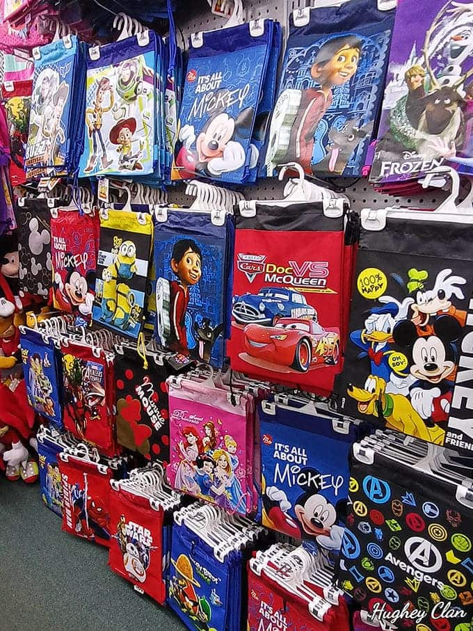 Colorful character bags featuring beloved Disney faces hang in neat rows, promising to carry vacation treasures home with cartoon flair.