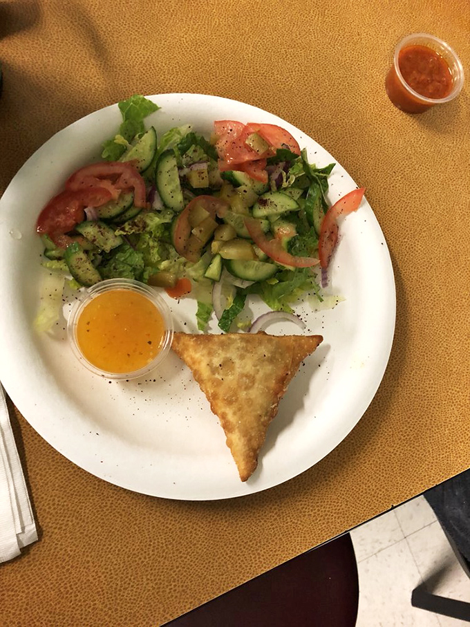 A perfect starter: fresh salad with herbs and spices alongside a golden-fried samosa. Simple food elevated by quality ingredients and tradition.