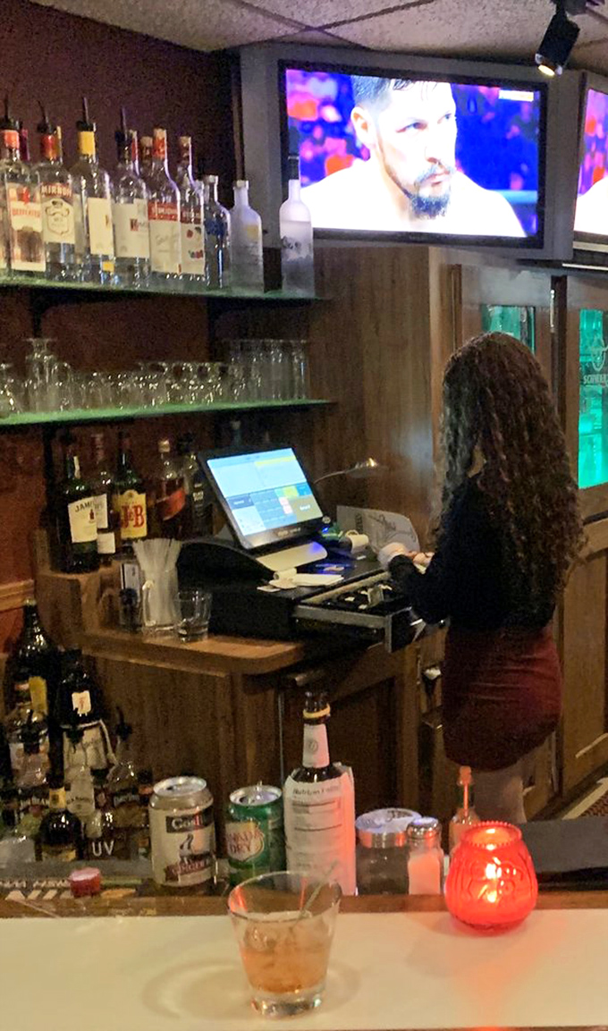 A bartender crafts drinks with practiced precision while sports play overhead &ndash; multitasking mastery in Wisconsin's favorite gathering spot.