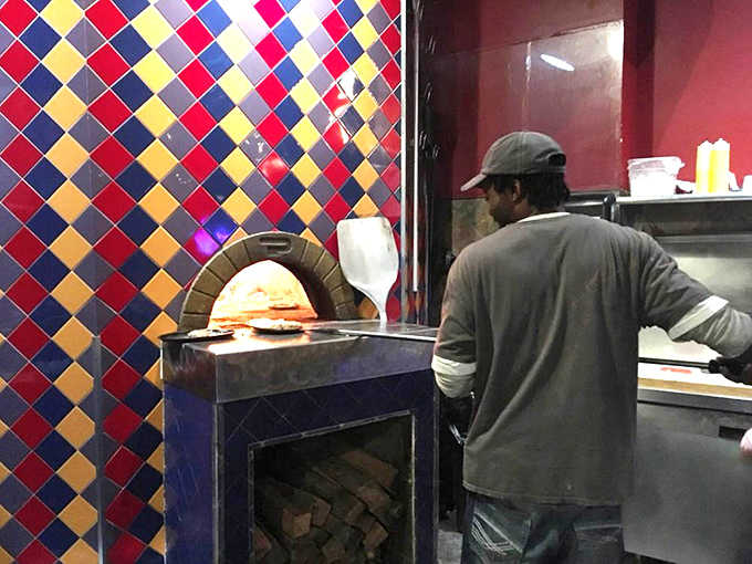 The wood-fired oven takes center stage in the kitchen, where skilled hands craft pizzas and other dishes with that signature smoky flavor.