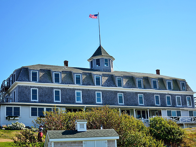 The historic inn stands proudly against blue skies, its flag snapping in the breeze that carries whispers of maritime tales.
