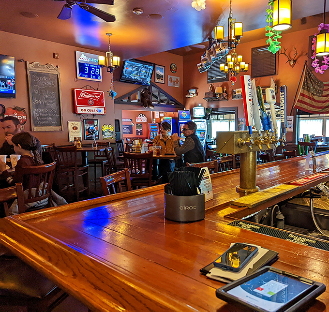 At the bar counter, polished wood gleams under ambient lighting, creating the perfect perch for solo diners or couples enjoying craft beers.