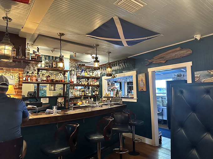 The intimate bar area invites lingering conversations over craft cocktails beneath the Scottish flag and nautical lighting.
