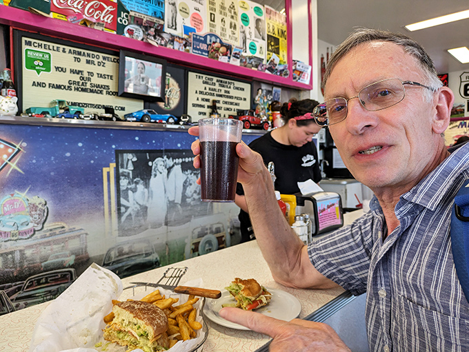 A satisfied customer enjoys the perfect combination – a hearty sandwich, golden fries, and that famous root beer to wash it all down.
