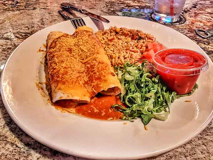 This enchilada isn't just a meal, it's a commitment – smothered in sauce and cheese with perfectly seasoned rice on the side.