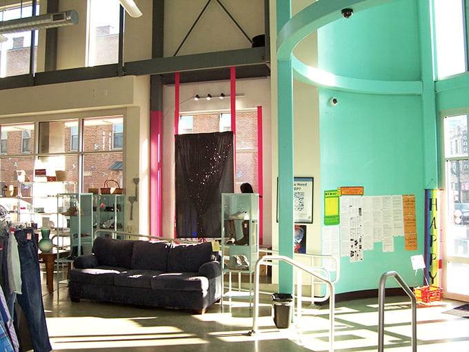 Sunlight floods the open interior, where industrial elements meet colorful displays in perfect thrift store harmony.