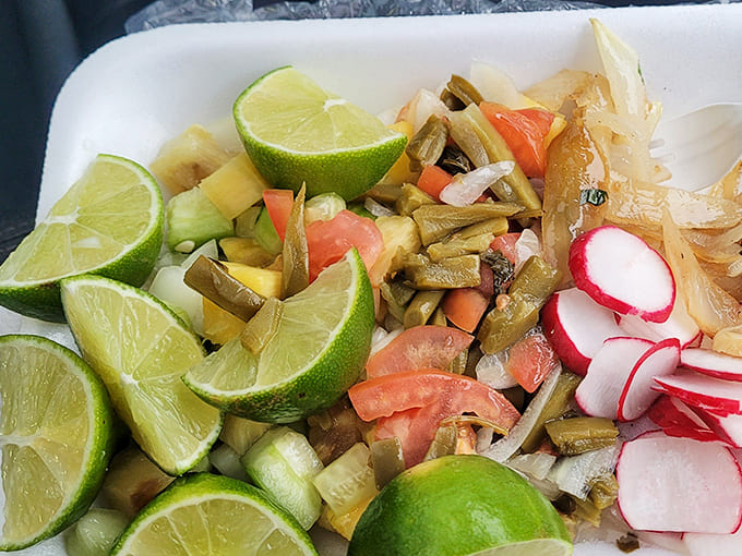 The finishing touches: Fresh lime wedges, crisp radishes, and grilled vegetables – the supporting cast that elevates every taco experience.