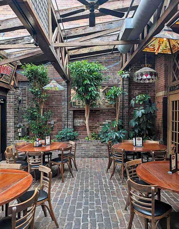 The atrium dining area brings the outdoors in with lush greenery, brick pathways, and a soaring ceiling that creates an unexpected oasis.