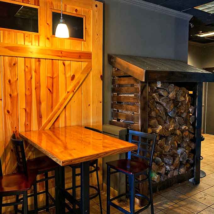 Rustic wood tables and a display of actual firewood, reminding you that real barbecue requires real fire, not some electric smoker shortcut.