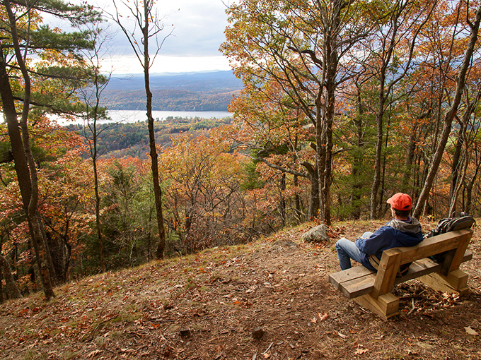 From this wooden bench perched high above Lake St. Catherine, autumn's masterpiece unfolds like a living painting that changes with each passing cloud.