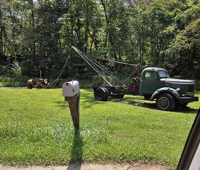A vintage truck rests in nearby countryside, a mechanical sentinel watching over farmland that rolls toward the horizon like a green ocean.