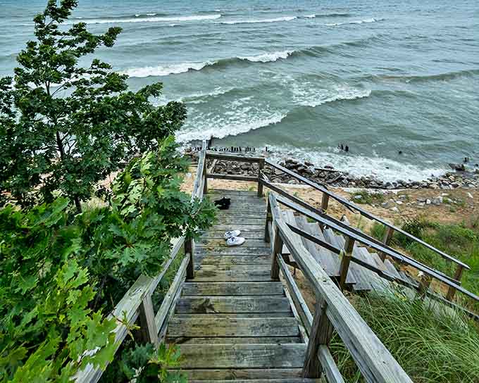 Wooden stairs descend dramatically to meet the shoreline, inviting brave souls to make the journey from forest to beach.