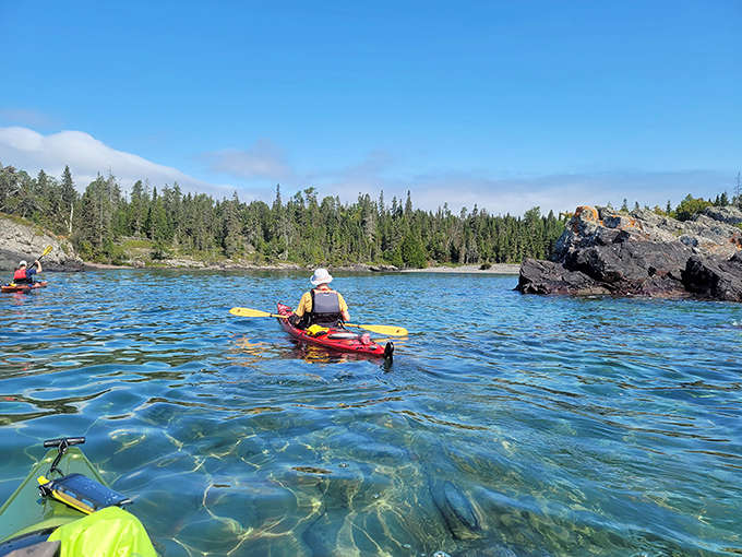 Kayakers glide through Isle Royale's remarkably clear waters, where paddling reveals shipwrecks, underwater geology, and unparalleled shoreline views.