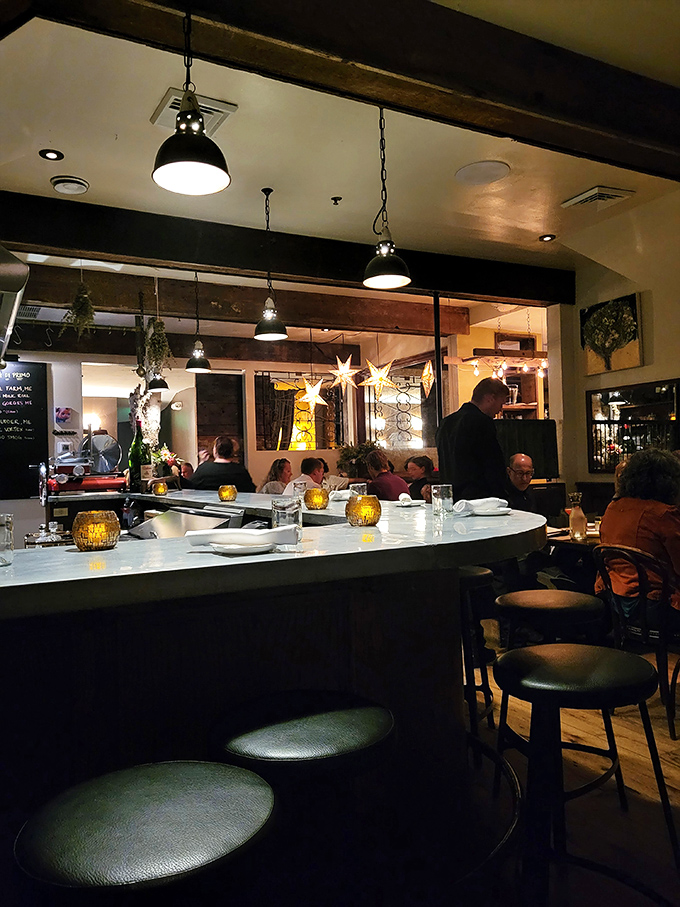 A marble-topped counter surrounded by comfortable stools invites guests to settle in for an evening of culinary exploration and expertly crafted drinks.