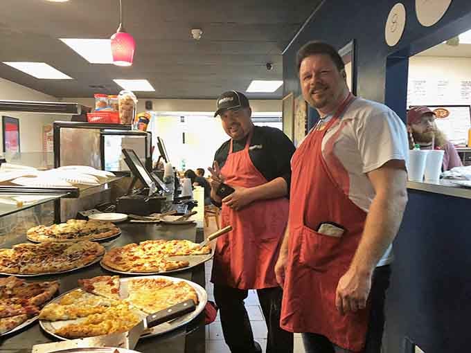Behind the counter, pizza artisans work their magic with practiced efficiency, transforming simple ingredients into slices of happiness.
