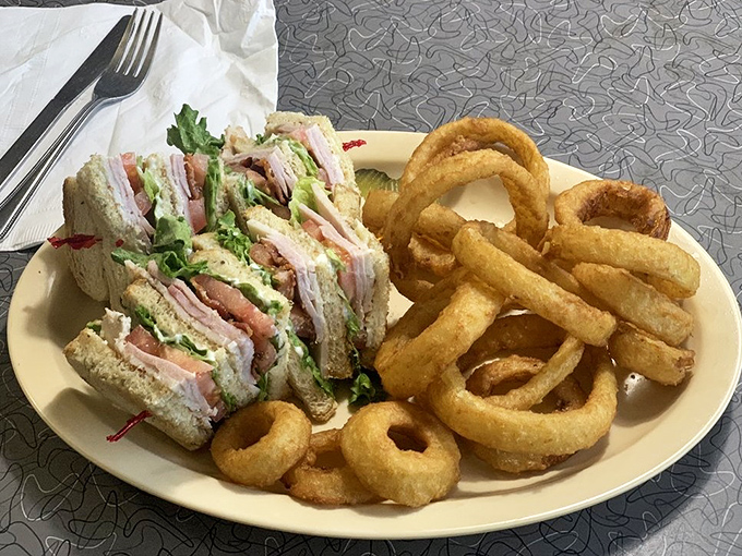Mel's club sandwich stands tall and proud, a skyscraper of flavor held together by tradition and those essential toothpicks.