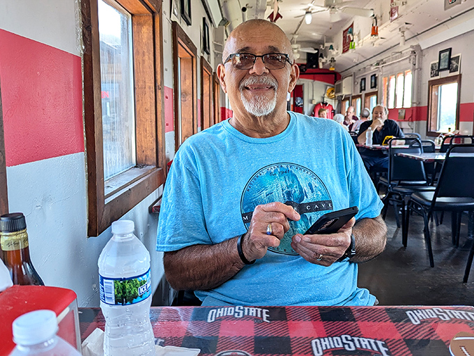 A friendly patron enjoys the unique dining experience, surrounded by the train car's nostalgic charm and Ohio State memorabilia.