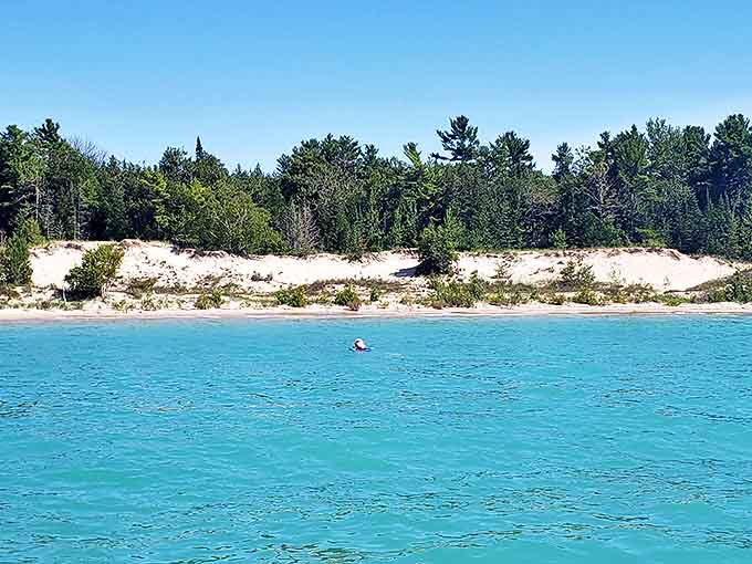 Emerald waters stretch toward the horizon, making you wonder if you've somehow teleported to a tropical paradise while driving through Michigan.