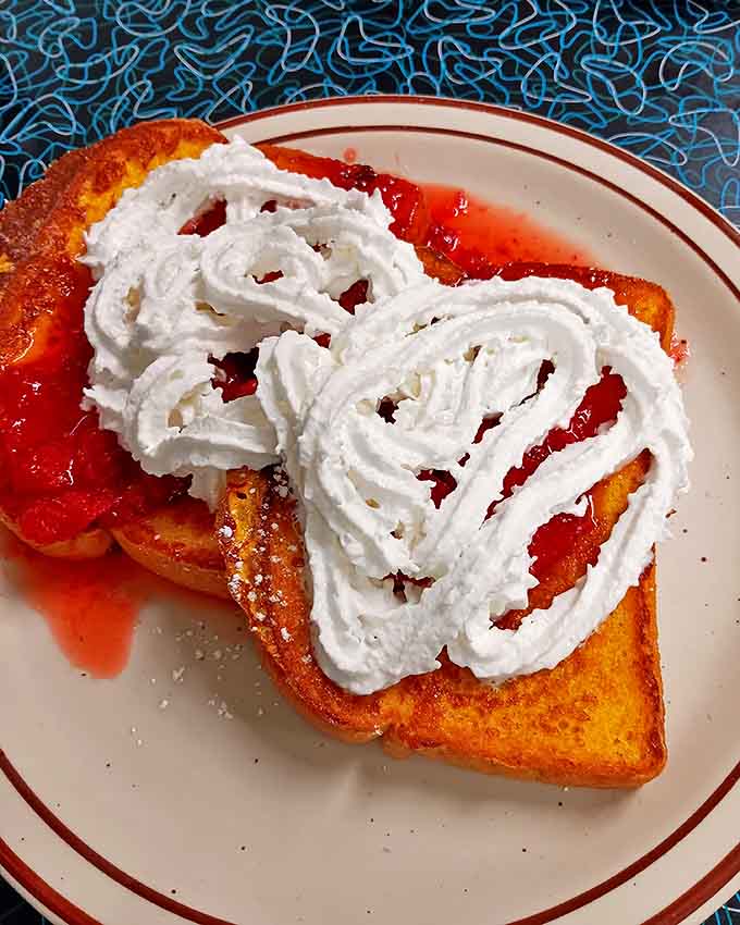 French toast that's crossed the line from breakfast to dessert, with strawberry topping and whipped cream applied with joyful abandon.