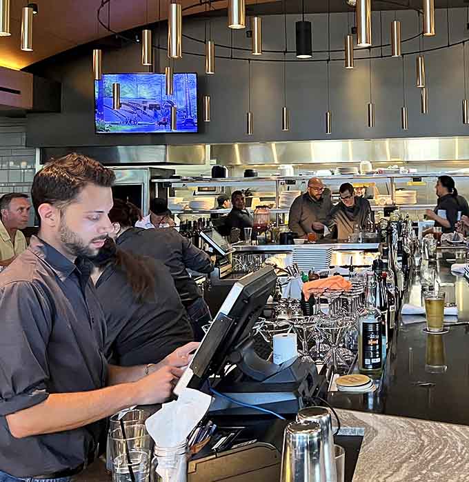 Attentive staff members coordinate seamlessly at the bar, ensuring drinks and orders flow smoothly throughout the busy restaurant.