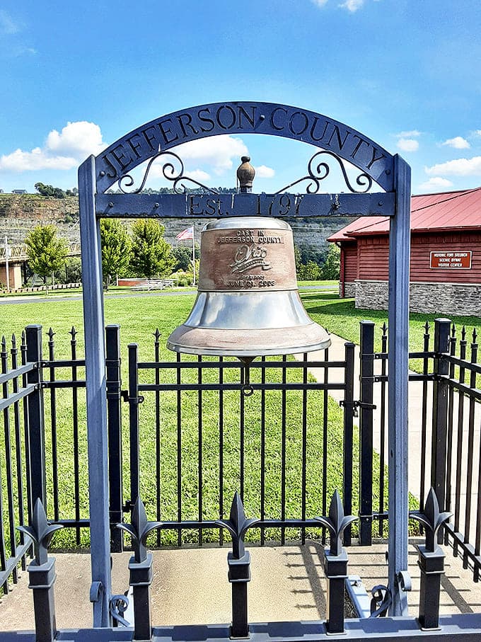 Jefferson County's historic bell stands as a silent witness to centuries of American history, protected behind ornate iron fencing.