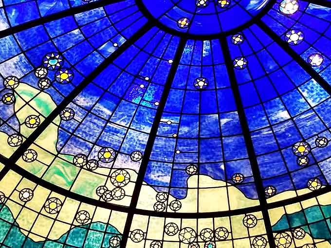 The museum's breathtaking stained glass dome transforms ordinary daylight into a celestial experience, with stars twinkling across a heavenly blue expanse.