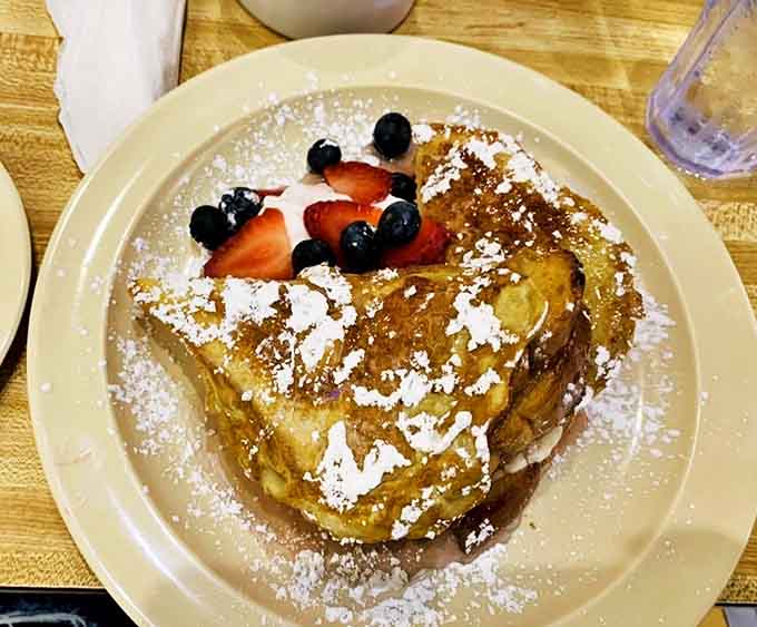 This isn't ordinary French toast &ndash; it's a sweet masterpiece topped with fresh berries and a dusting of powdered sugar that melts into the warm, custardy bread.