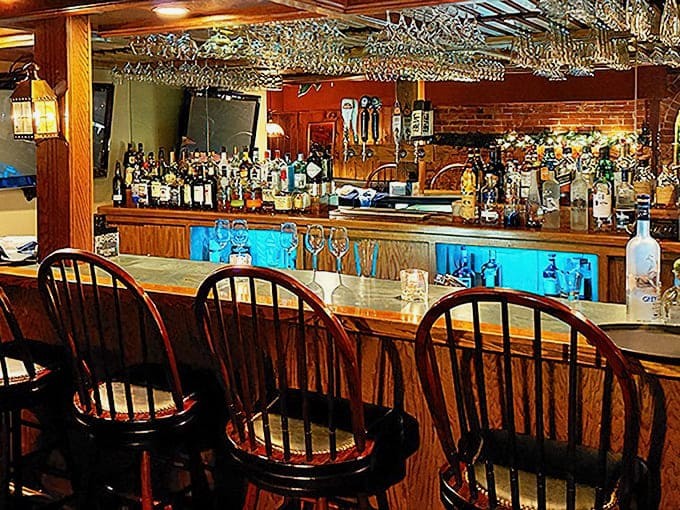 The bar glows with amber warmth, where glasses hang like stalactites and spirits stand at attention, ready for duty.