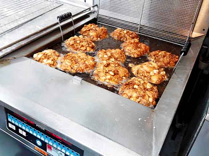 Apple fritters sizzle in hot oil, transforming from simple dough to golden-brown masterpieces. The anticipation is almost as delicious as the donuts themselves.
