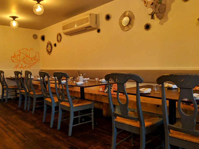 The dining room's rustic elegance creates the perfect backdrop for memorable meals. Blue chairs add pops of color against warm wood tables where culinary memories are made.