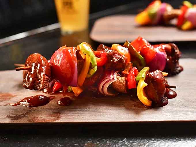 Colorful kebabs sizzle with flavor, offering one-handed eating perfection between turns at the axe-throwing lanes or arcade cabinets.