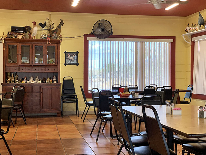 Another angle of the dining room reveals more roosters and the warm, welcoming atmosphere that makes strangers feel like regulars. Those vertical blinds filter the harsh desert sun perfectly.