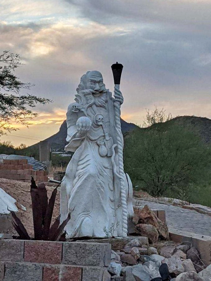 This imposing wizard statue stands guard over the castle grounds, torch raised high against the twilight sky.