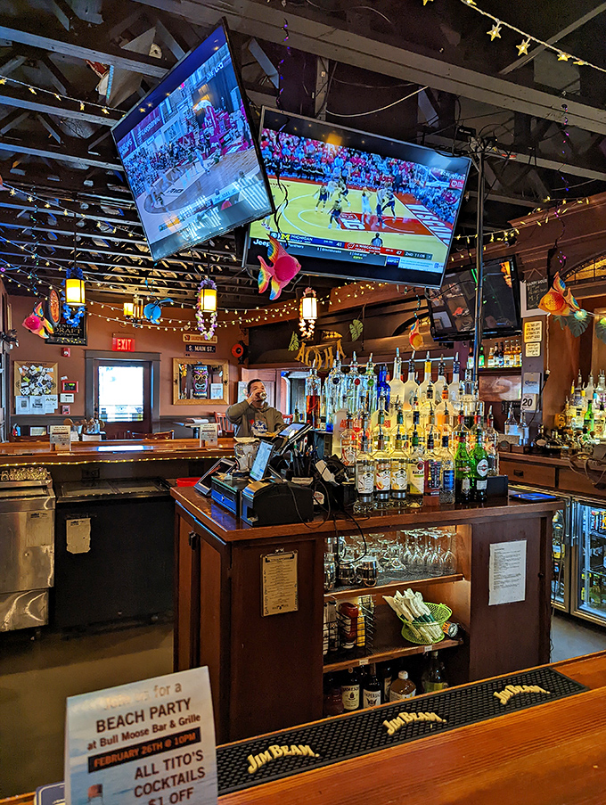The fully-stocked bar area buzzes with energy as bartenders craft everything from classic cocktails to creative concoctions beneath twinkling string lights.