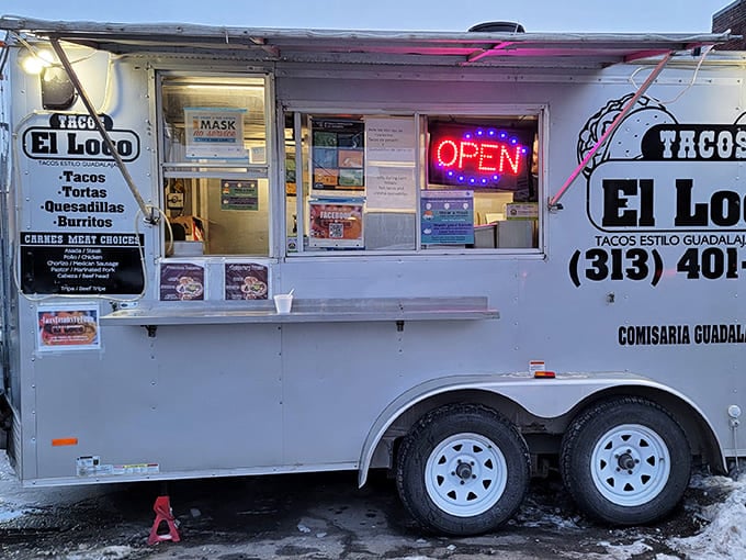 Winter transforms the breakwater into a snow-dusted pathway, leading to the steadfast lighthouse against steel-gray waters.