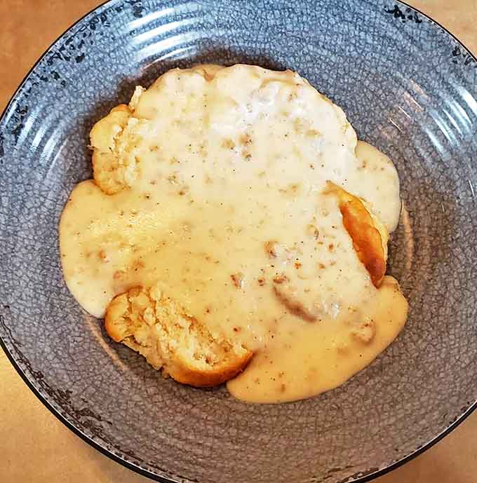 Biscuits swimming in creamy sausage gravy represent Southern comfort food at its finest, transported to Michigan with love and proper execution.