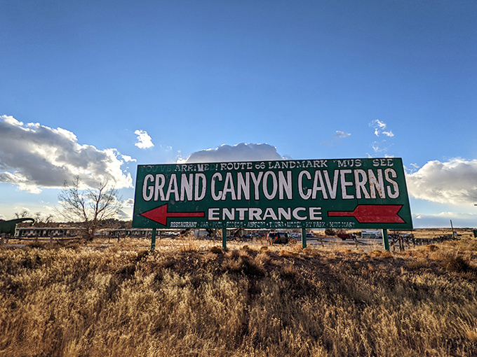 The weathered roadside sign points travelers toward adventure, a classic piece of Americana that's been directing explorers underground since Route 66's heyday.