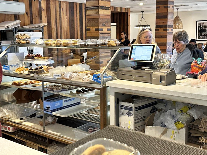 A busy bakery counter showcases tempting pastries as friendly staff assist guests with practiced ease.