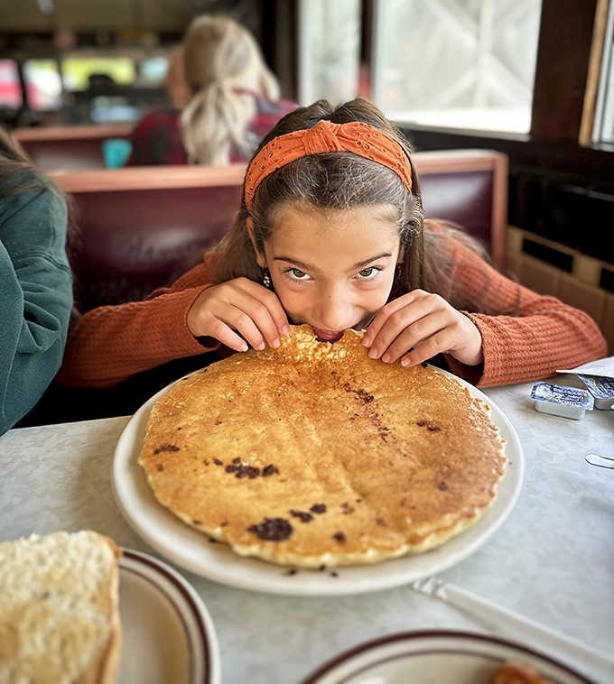 A young diner contemplates the circumference of her pancake &ndash; possibly the largest she's ever encountered outside of children's storybooks.